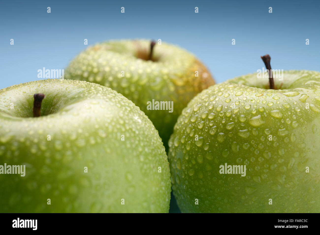 Wet green apple covered by water drops on coloured background ...