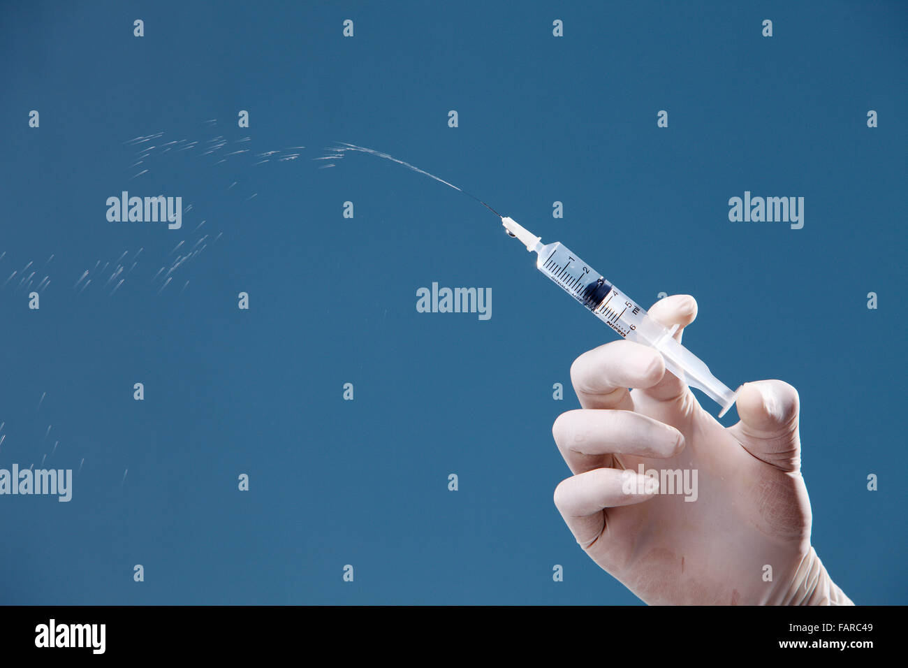 Hand holding syringe isolated on coloured background Stock Photo - Alamy