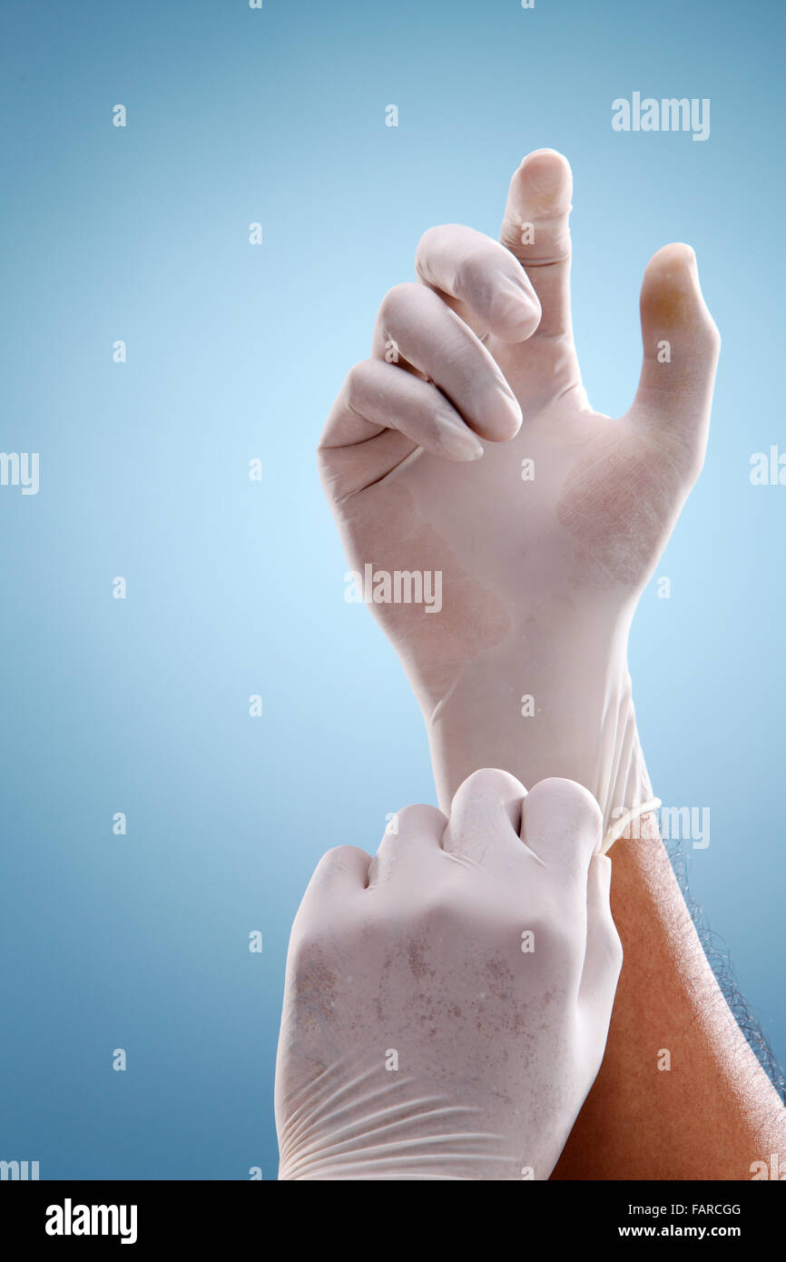 Hands putting on surgical gloves over a creative blue background Stock ...