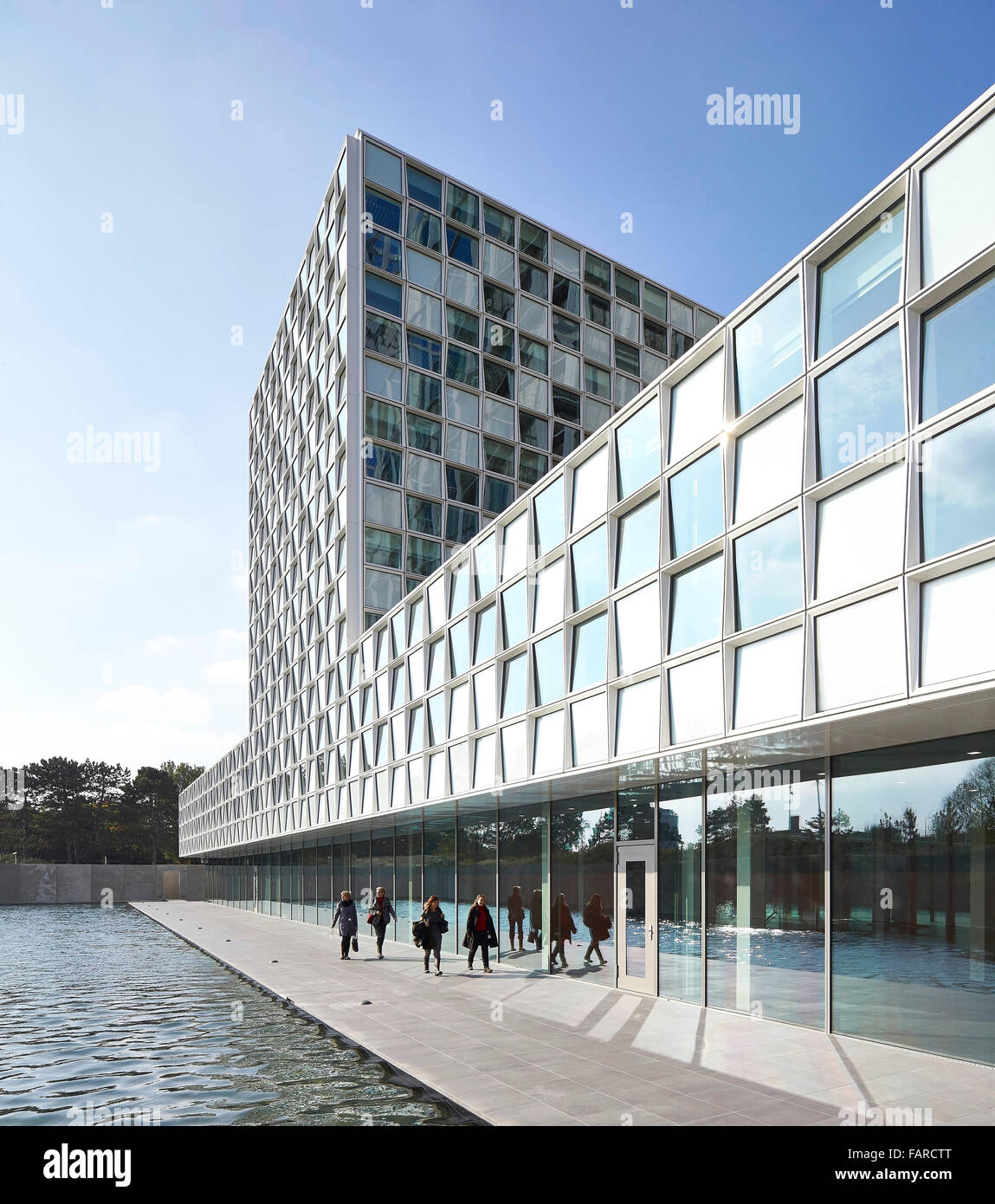 Perspective along exterior grid facade with moat-style pond and visitor ...