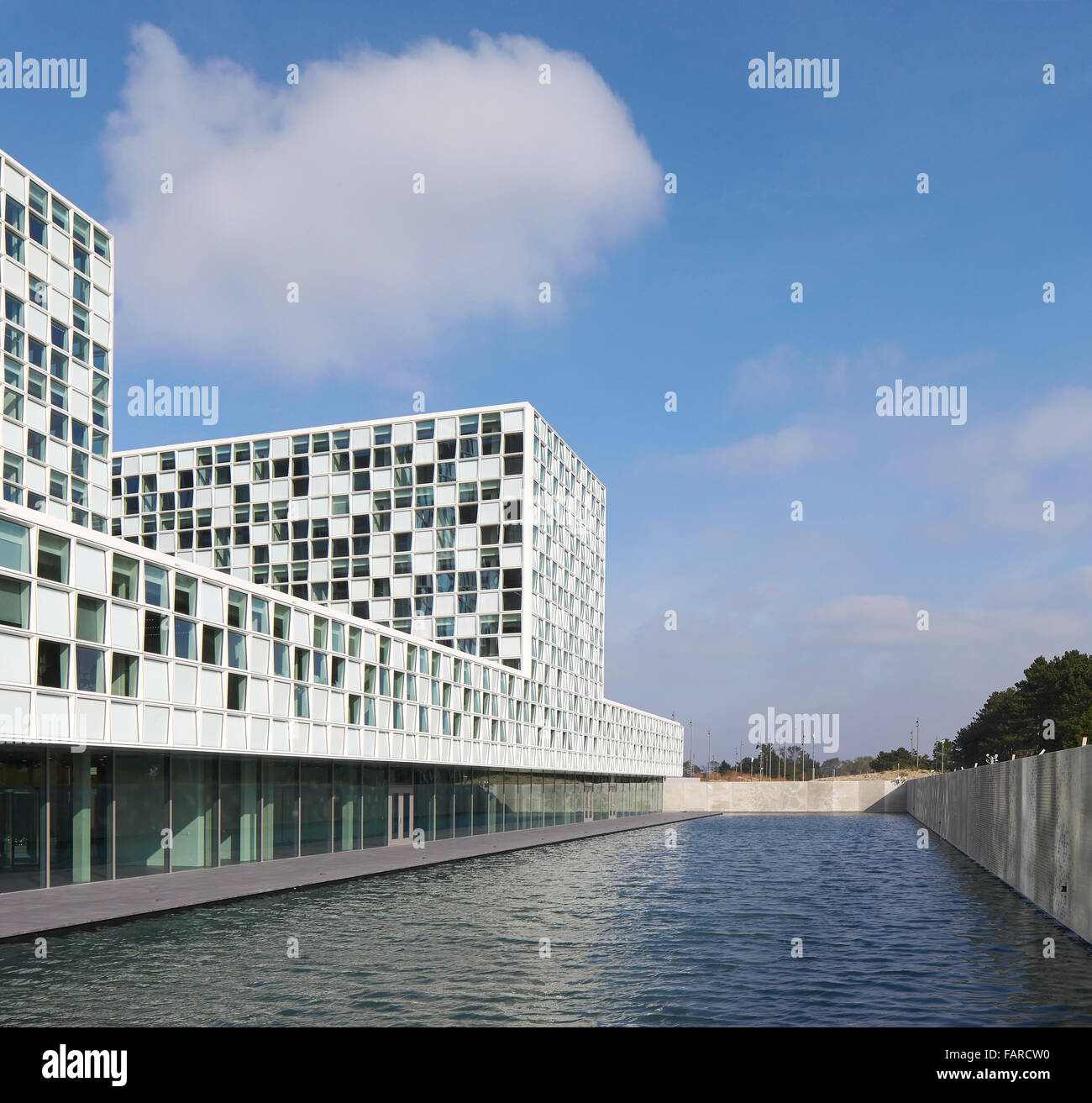 Perspective along exterior grid facade with moat-style pond ...