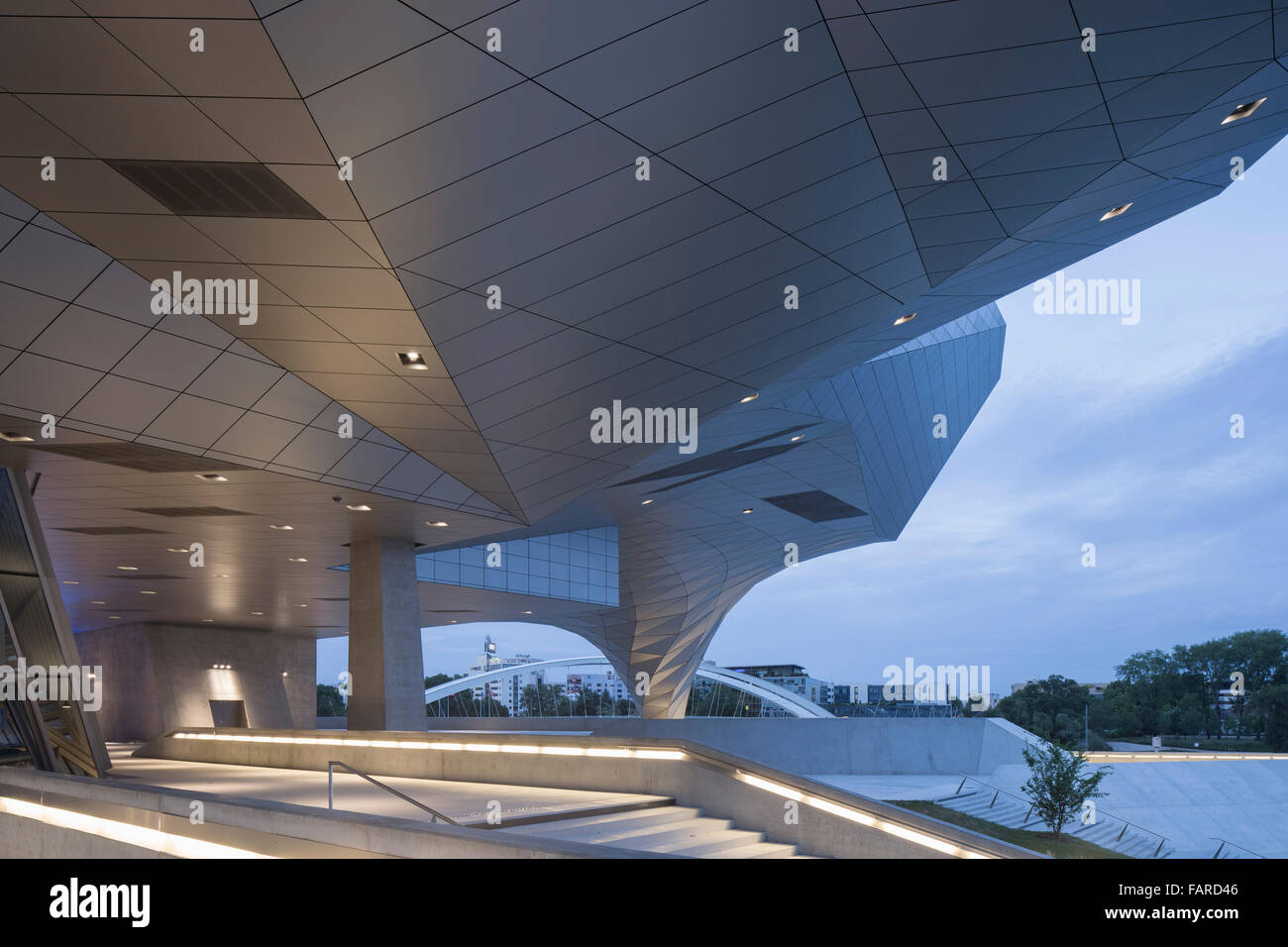 Public space underneath floating building structure at dusk. Musée des ...