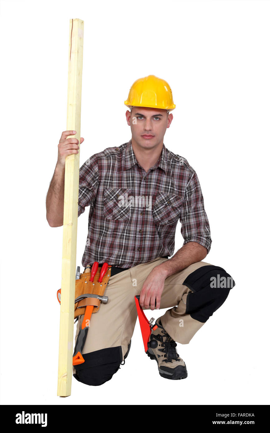 carpenter kneeling with plank of wood Stock Photo - Alamy
