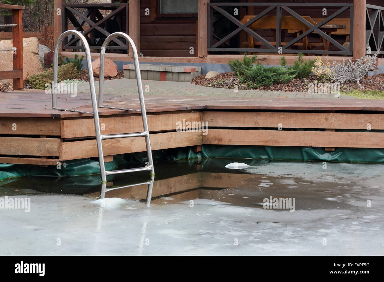 Fragment of the frozen ice lake and metal ladder for descent in water ...