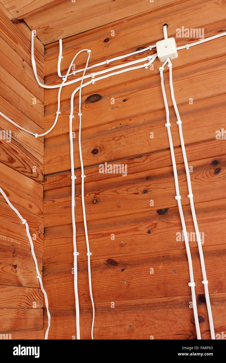 Fire dangerous electric white wires on a dry wooden wall of the rural ...