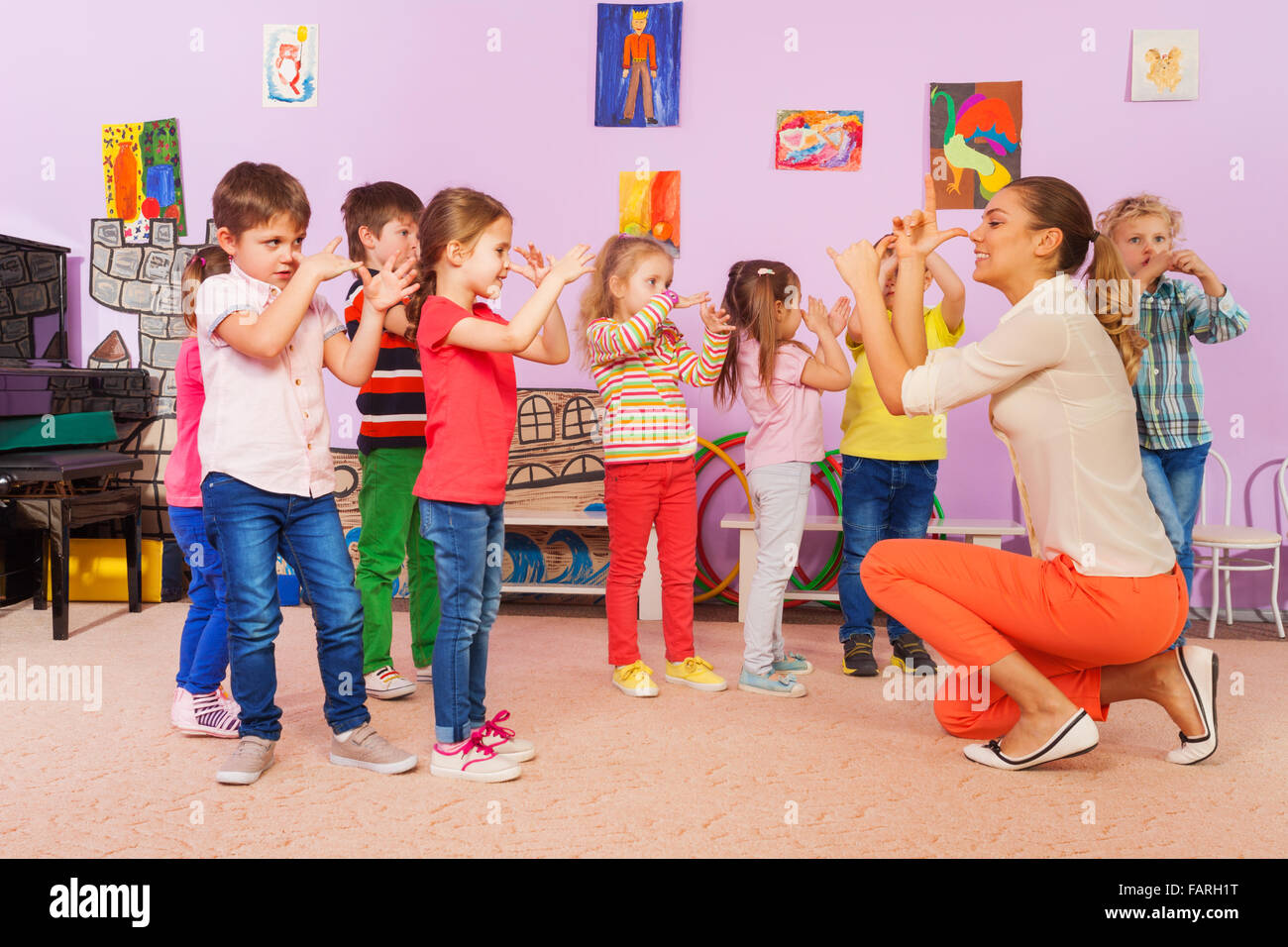 Kids repeat after teacher gesture in class Stock Photo - Alamy