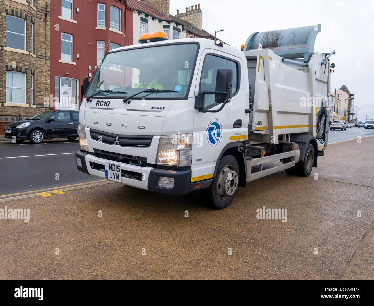 A small waste disposal vehicle collecting rubbish from litter bins on ...