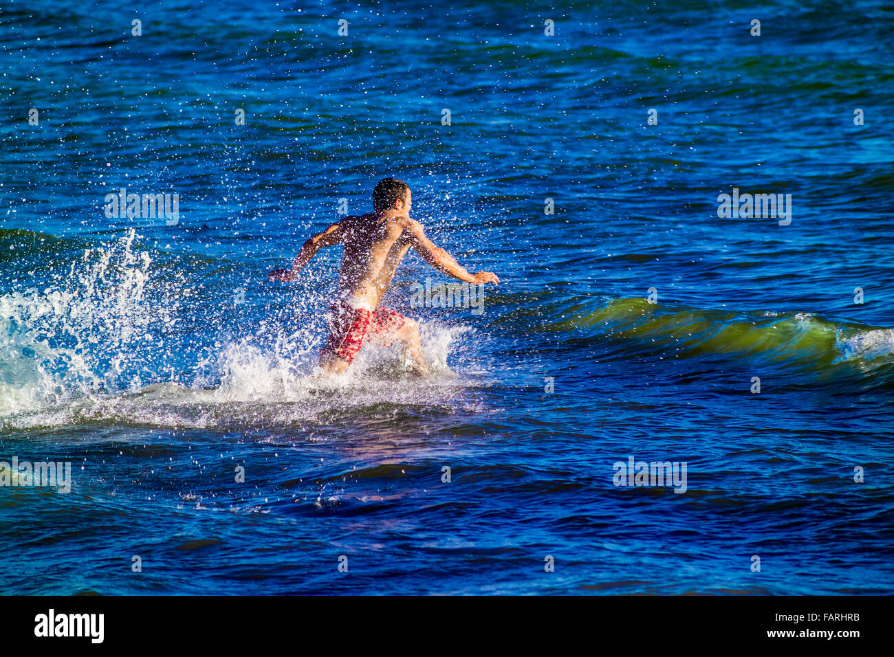 Man running into the waves splashing water, St Kilda Beach, Melbourne ...