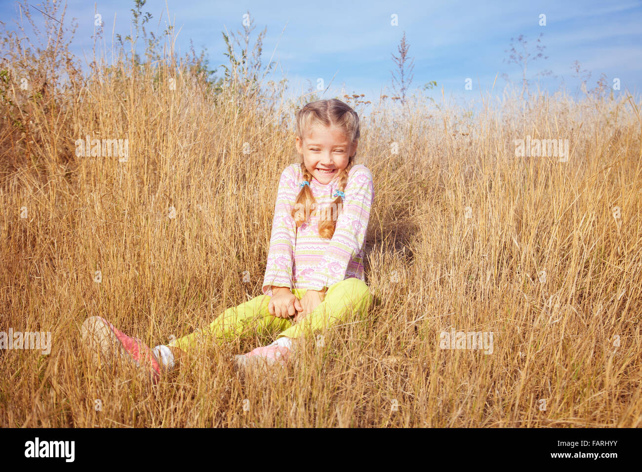 Cute girl sitting in the grass Stock Photo - Alamy