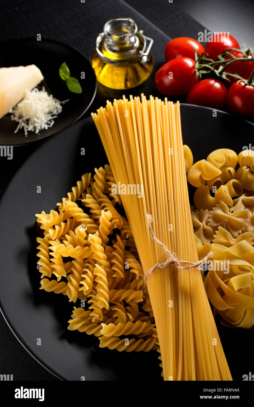 Raw mixed pasta with ingredients on black background Stock Photo - Alamy