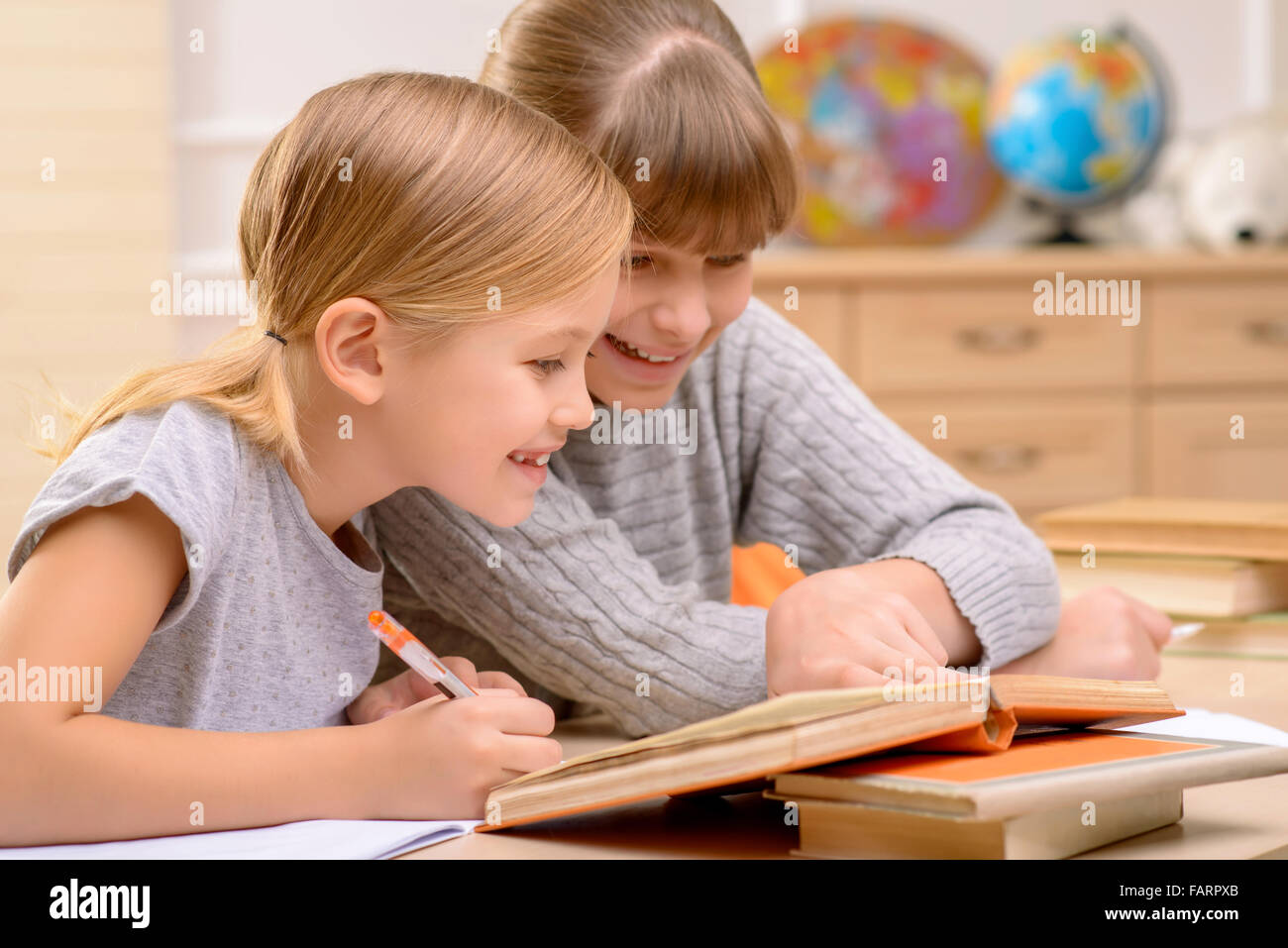 Pretty little girls sitting at the table Stock Photo - Alamy