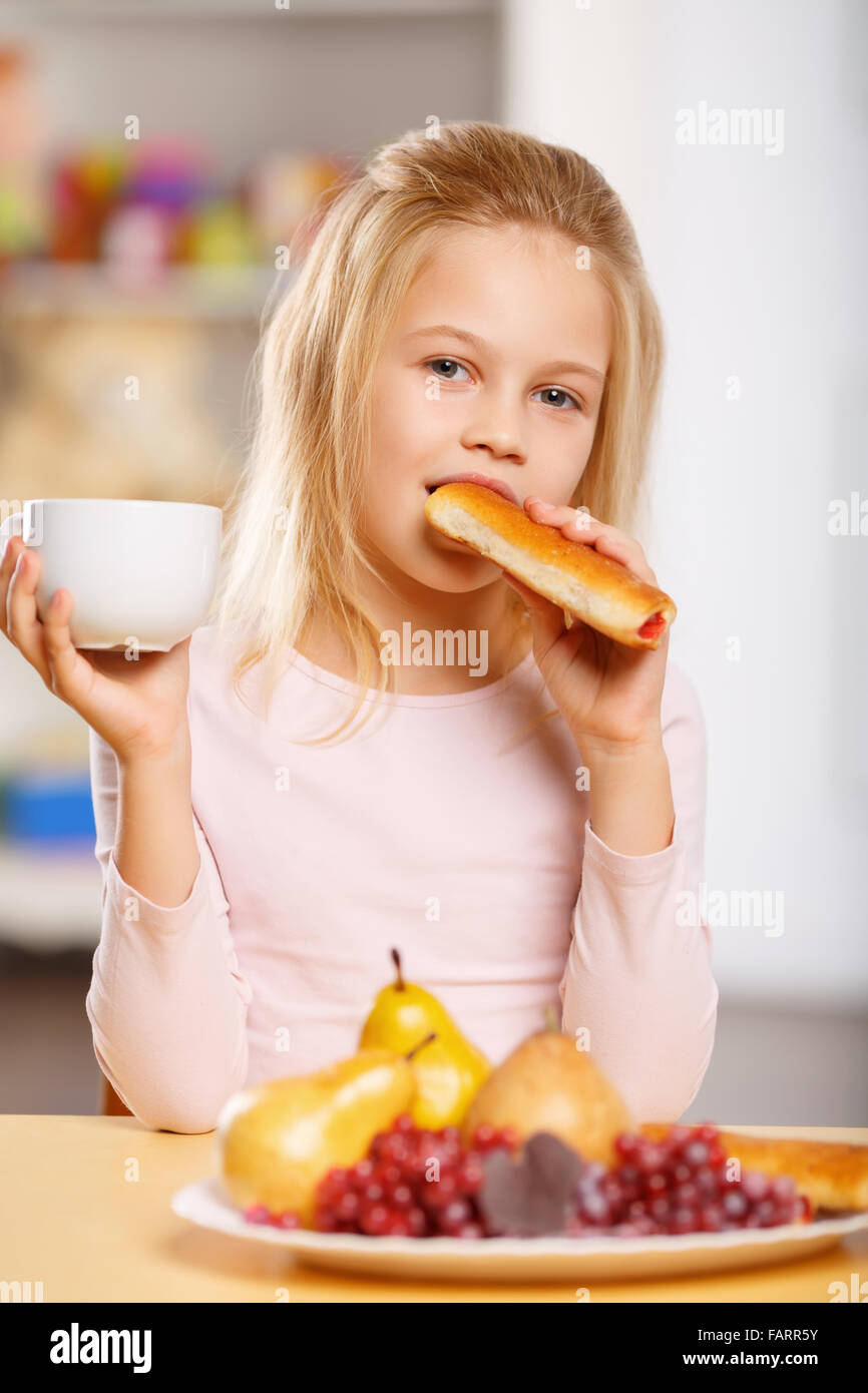 Little girl is drinking tea and eating pastry Stock Photo - Alamy
