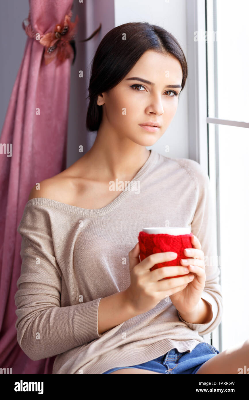 Young woman sitting near window Stock Photo - Alamy