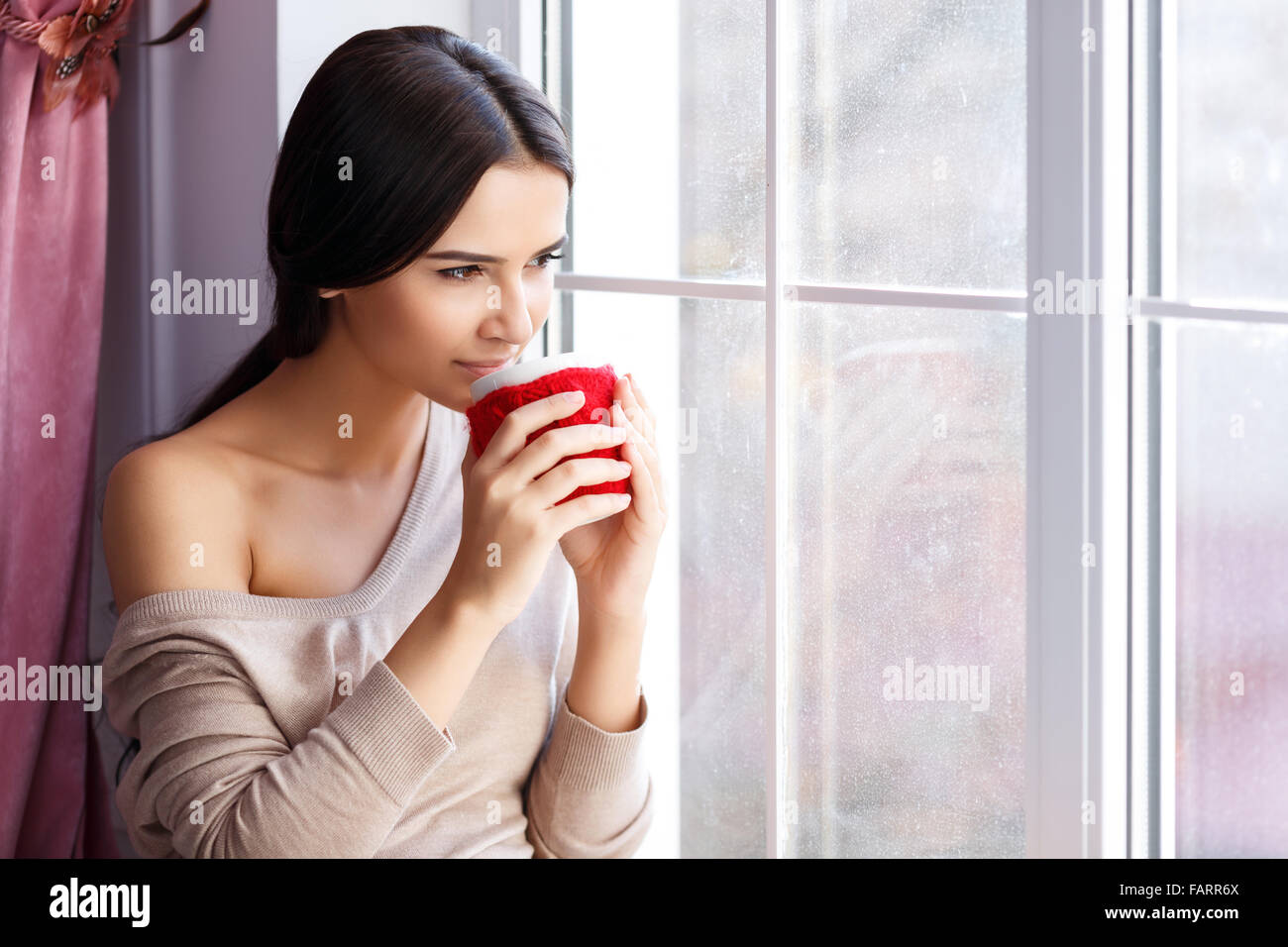 Young woman sitting near window Stock Photo - Alamy