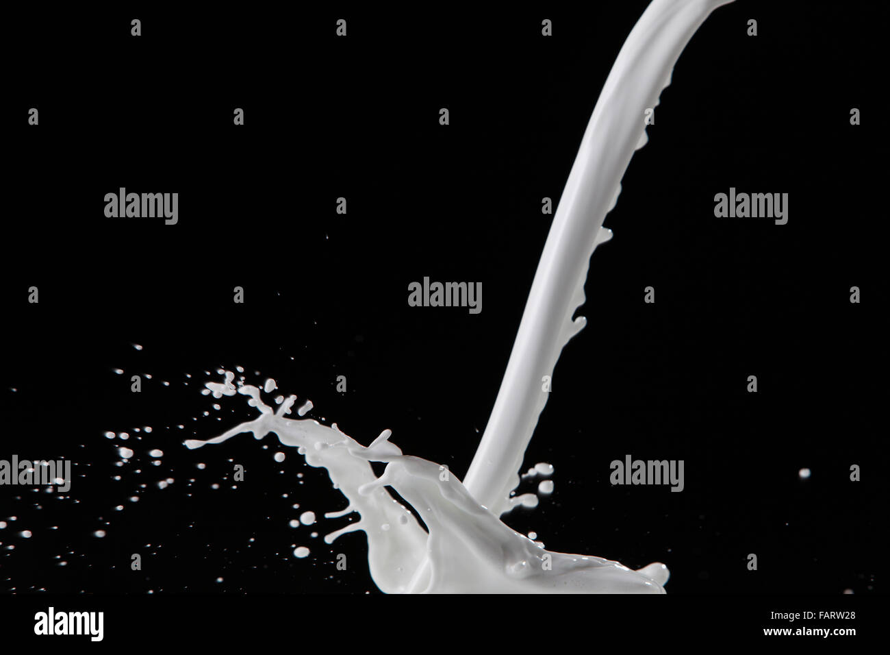 pouring milk on the black background Stock Photo - Alamy