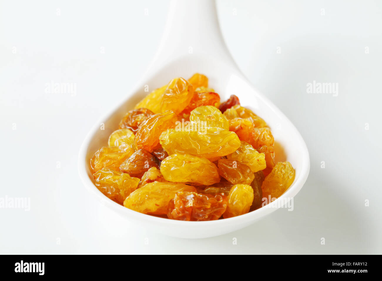 Golden-coloured raisins on a white spoon Stock Photo - Alamy
