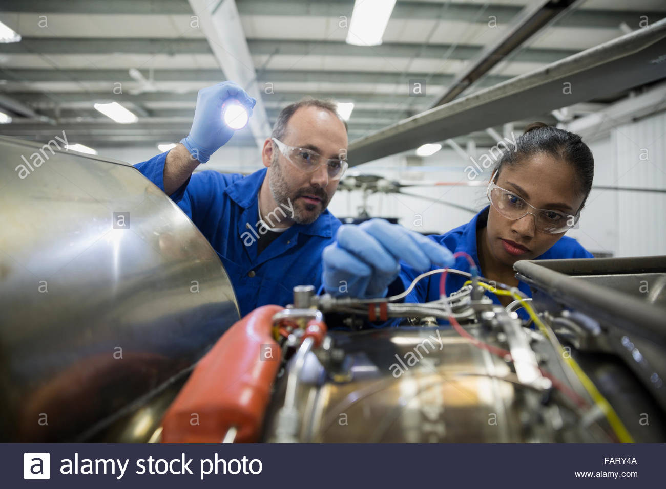 Helicopter mechanics working on part with flashlight Stock Photo - Alamy