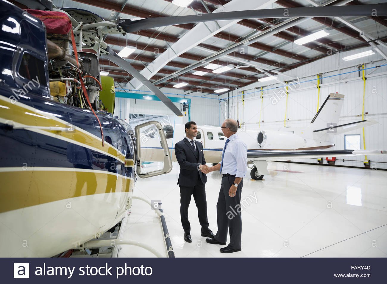 Pilot and manager handshaking at helicopter in airplane hangar Stock ...