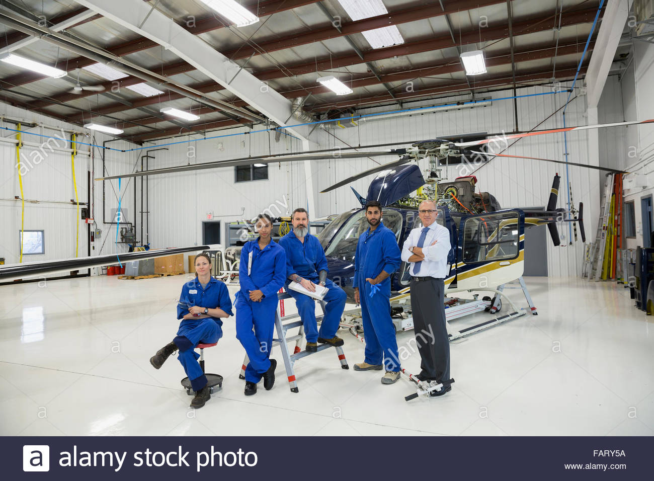 Portrait confident manager and helicopter mechanics airplane hangar ...