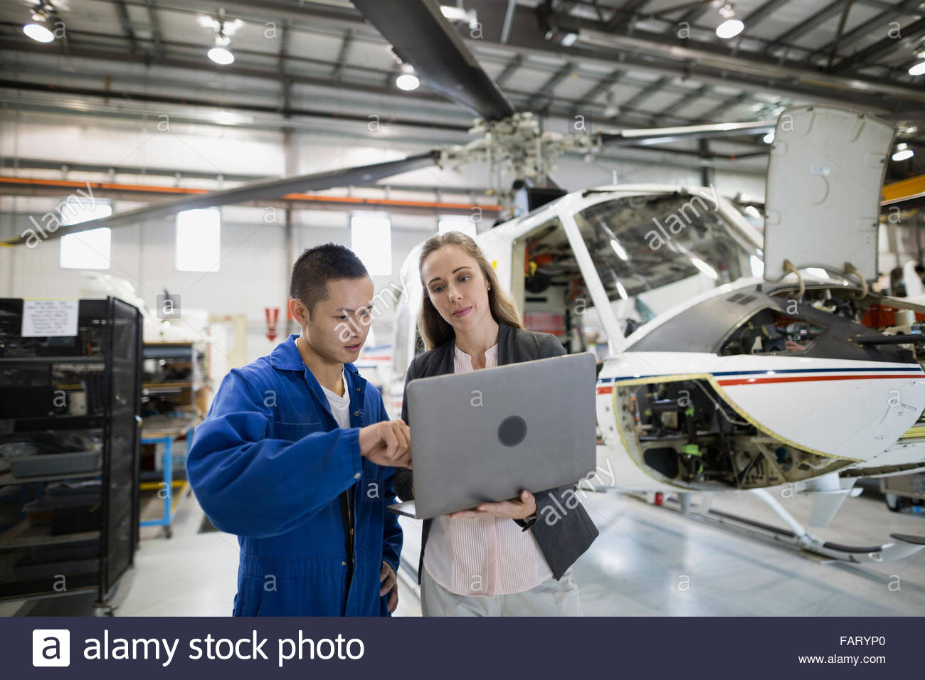 Manager and helicopter mechanic using laptop airplane hangar Stock ...