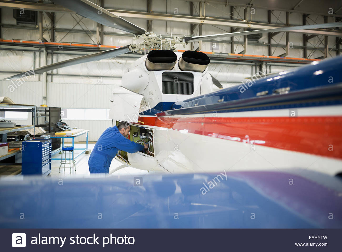 Helicopter mechanic repairing engine in airplane hangar Stock Photo - Alamy