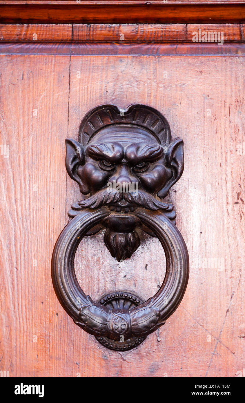 demon faced doorknocker on a wooden door Stock Photo - Alamy