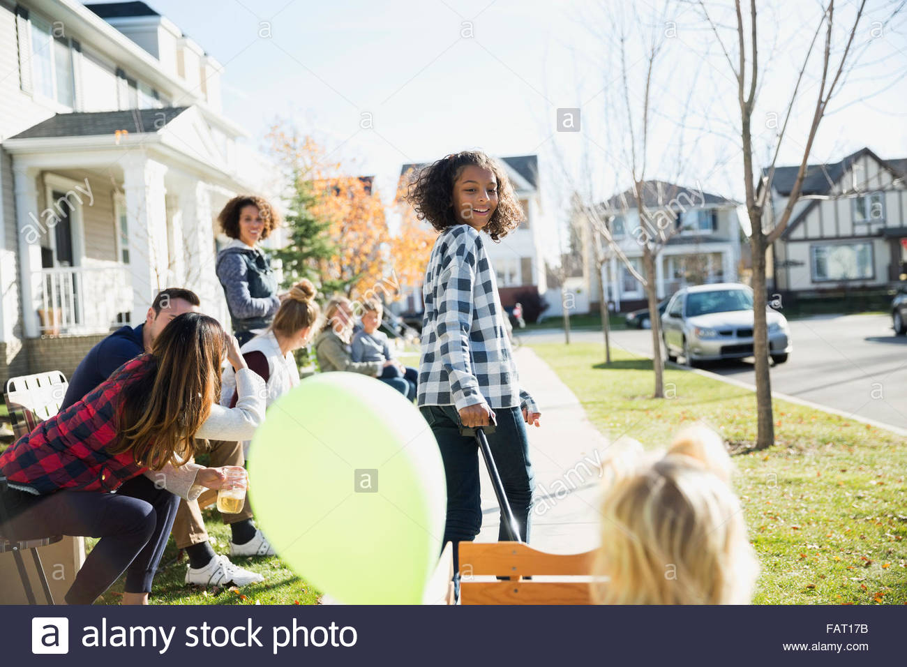 Girl pulling friend in wagon on neighborhood sidewalk Stock Photo - Alamy