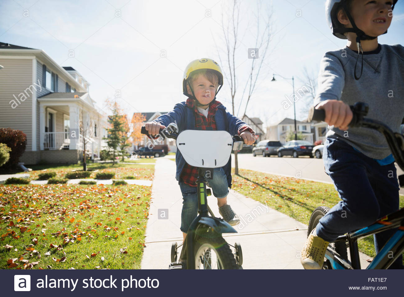 Boys riding bikes on autumn neighborhood sidewalk Stock Photo - Alamy