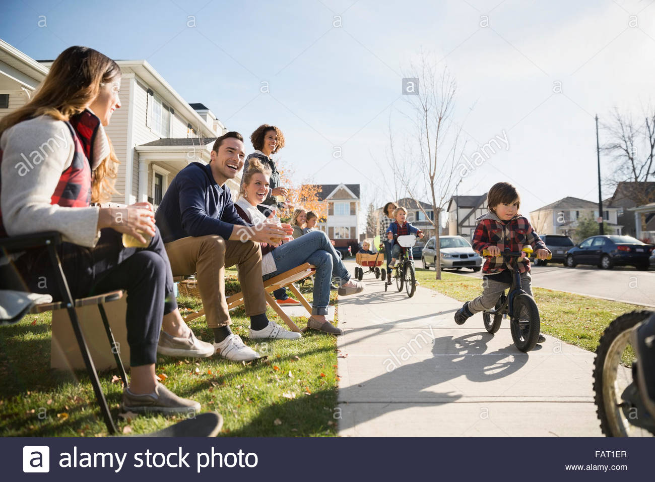 Neighbors watching kids ride bikes on sidewalk Stock Photo - Alamy