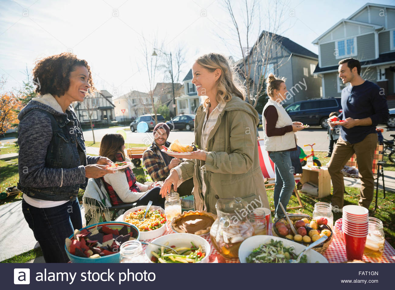 Neighbors enjoying potluck in sunny front yard Stock Photo - Alamy