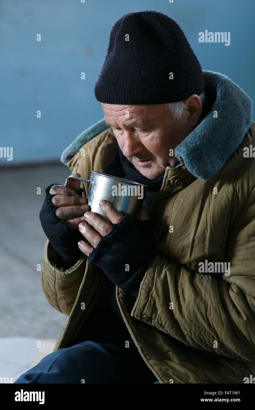 Homeless man holding his iron cup Stock Photo - Alamy