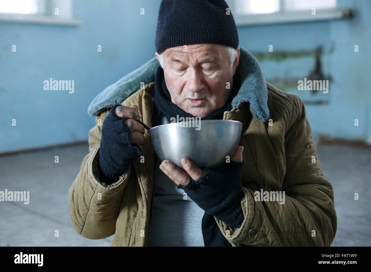 Homeless man is eating from his iron bowl Stock Photo - Alamy