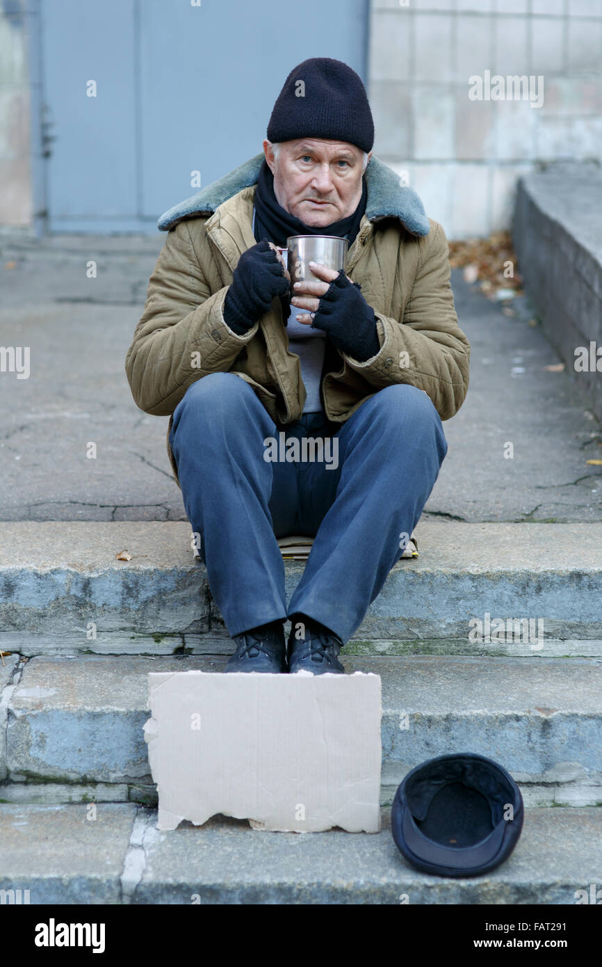 Homeless man holding his iron cup Stock Photo - Alamy