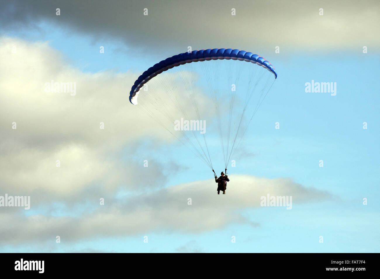 Pilot flying a paraglider against a blue sky perhaps with clouds Stock ...