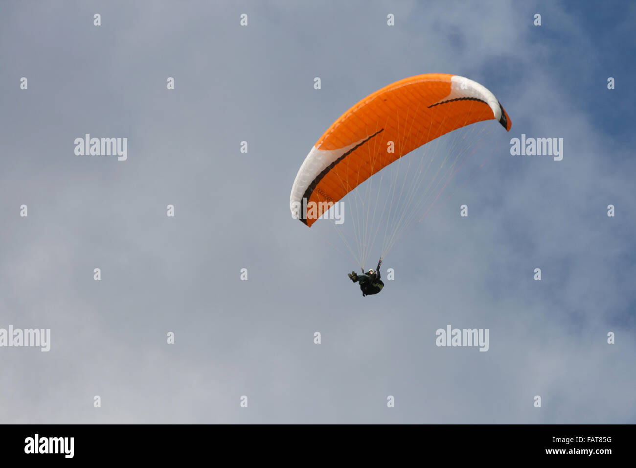 Pilot flying a paraglider against a blue sky perhaps with clouds Stock ...