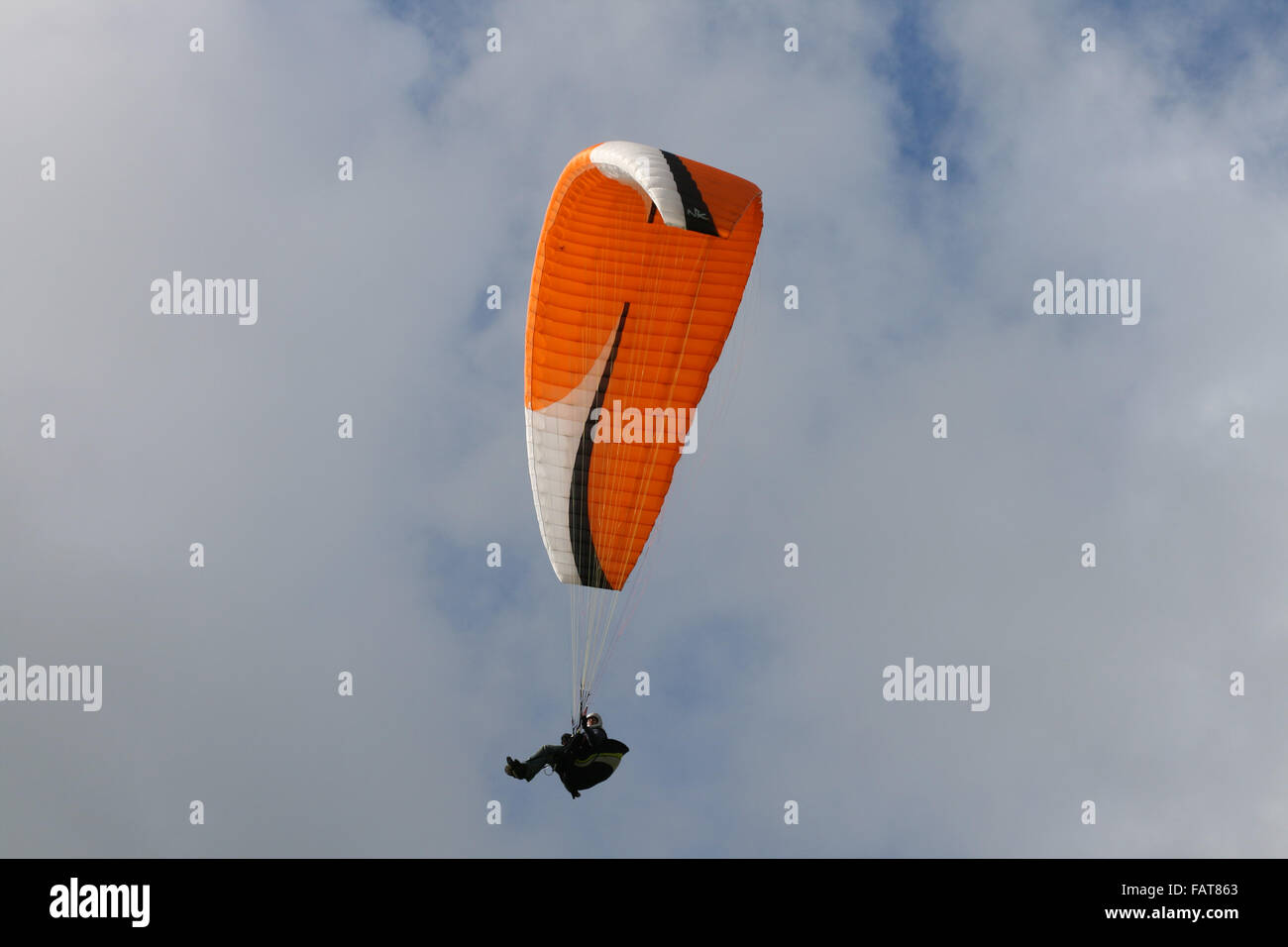 Pilot flying a paraglider against a blue sky perhaps with clouds Stock ...