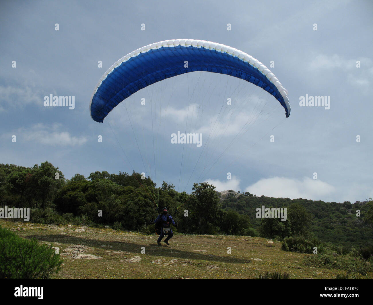 Pilot flying a paraglider against a blue sky Stock Photo - Alamy