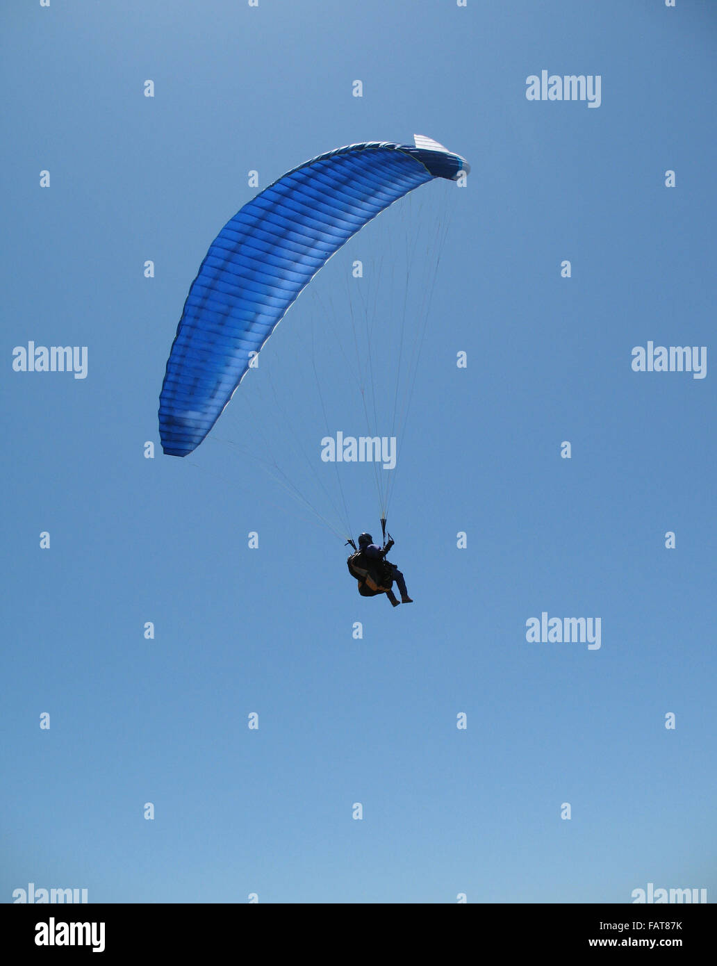 Pilot flying a paraglider against a blue sky Stock Photo - Alamy
