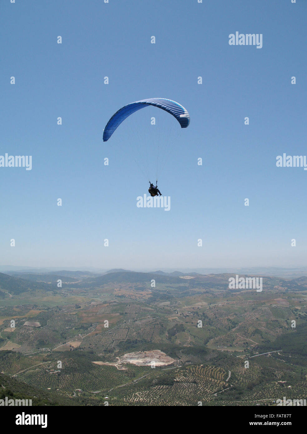 Pilot flying a paraglider against a blue sky Stock Photo - Alamy