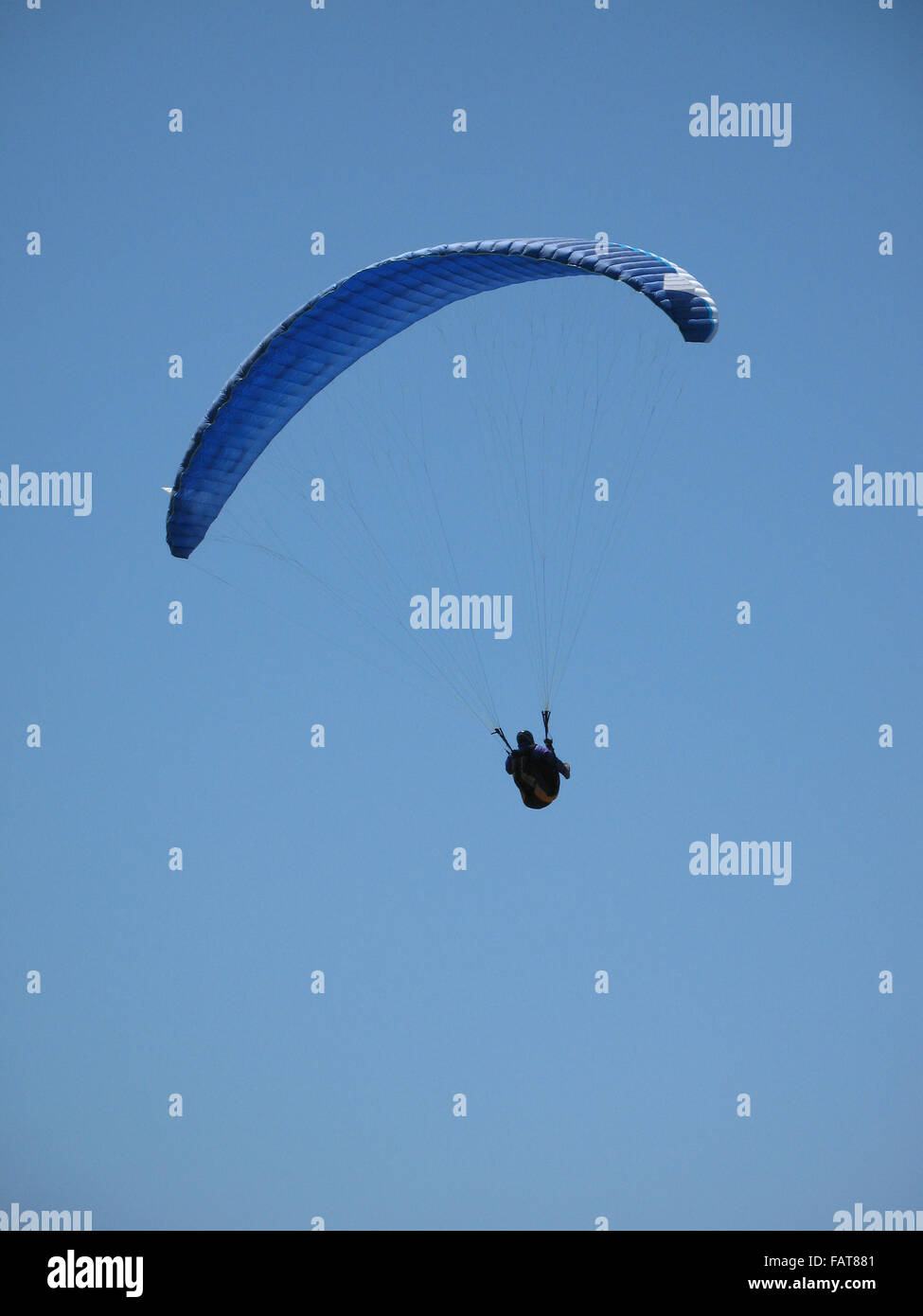 Pilot flying a paraglider against a blue sky Stock Photo - Alamy