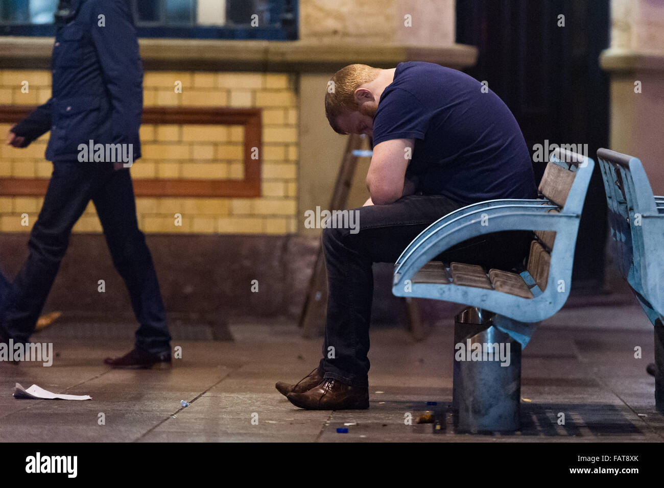 A man sits slumped on a bench on St Mary Street Stock Photo - Alamy