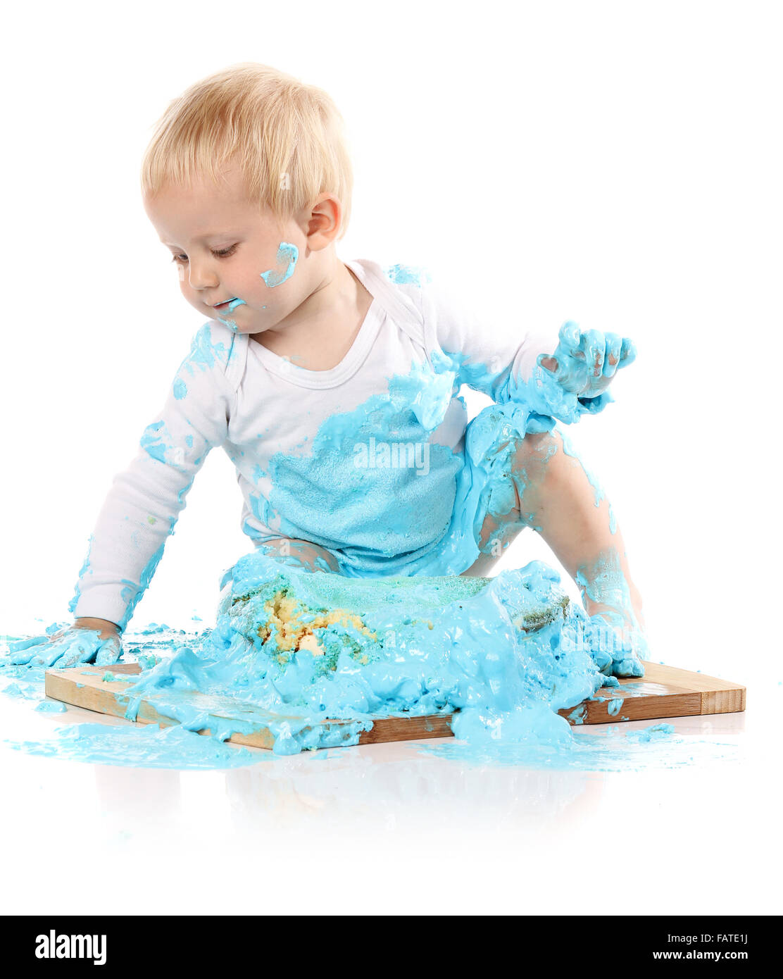 A one year old baby boy smashing a blue iced birthday cake on a wooden ...