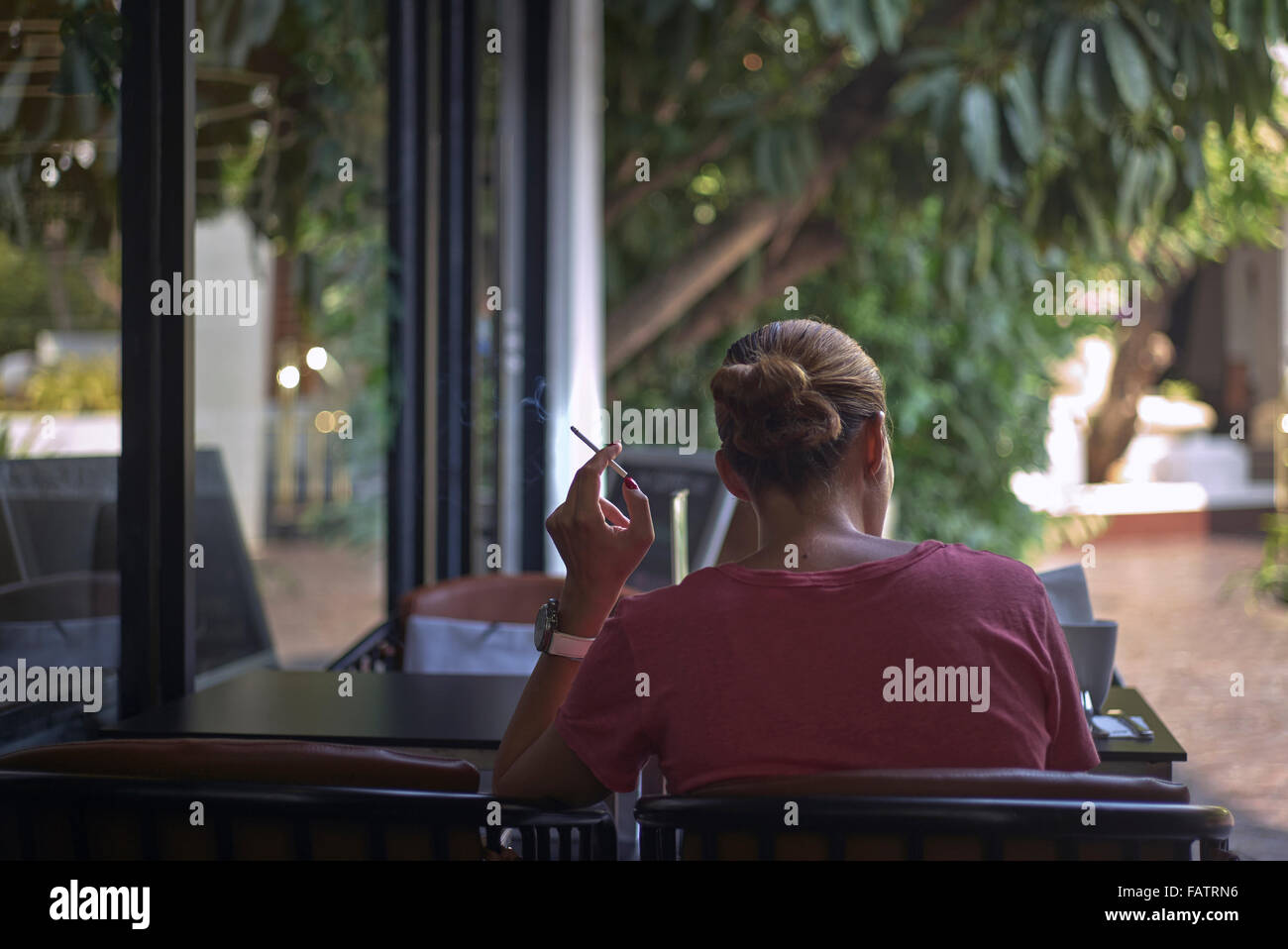 Woman smoker sat alone in the outside smoking area of a restaurant ...
