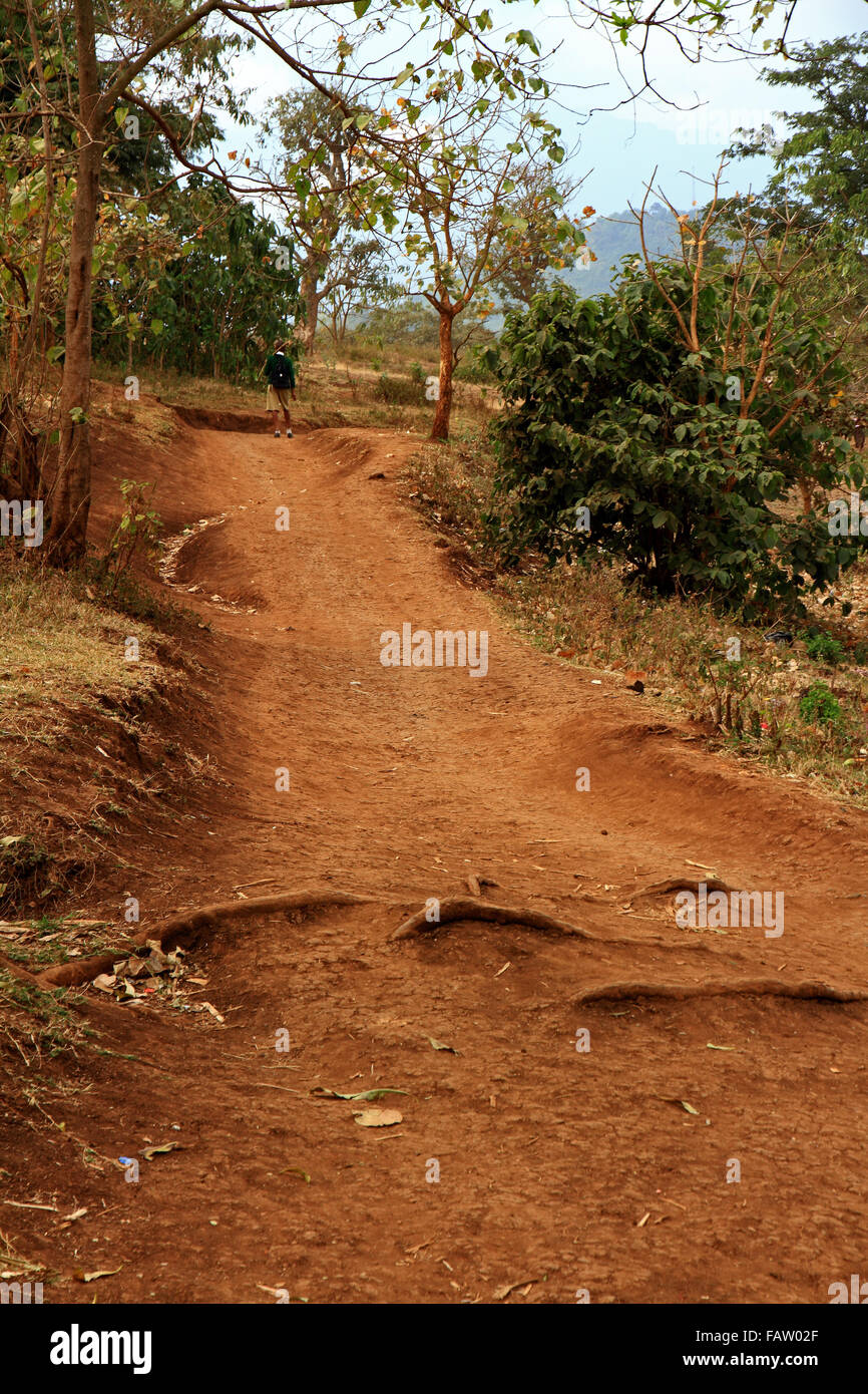 Looking up a dirt path with a small African school child in uniform at ...
