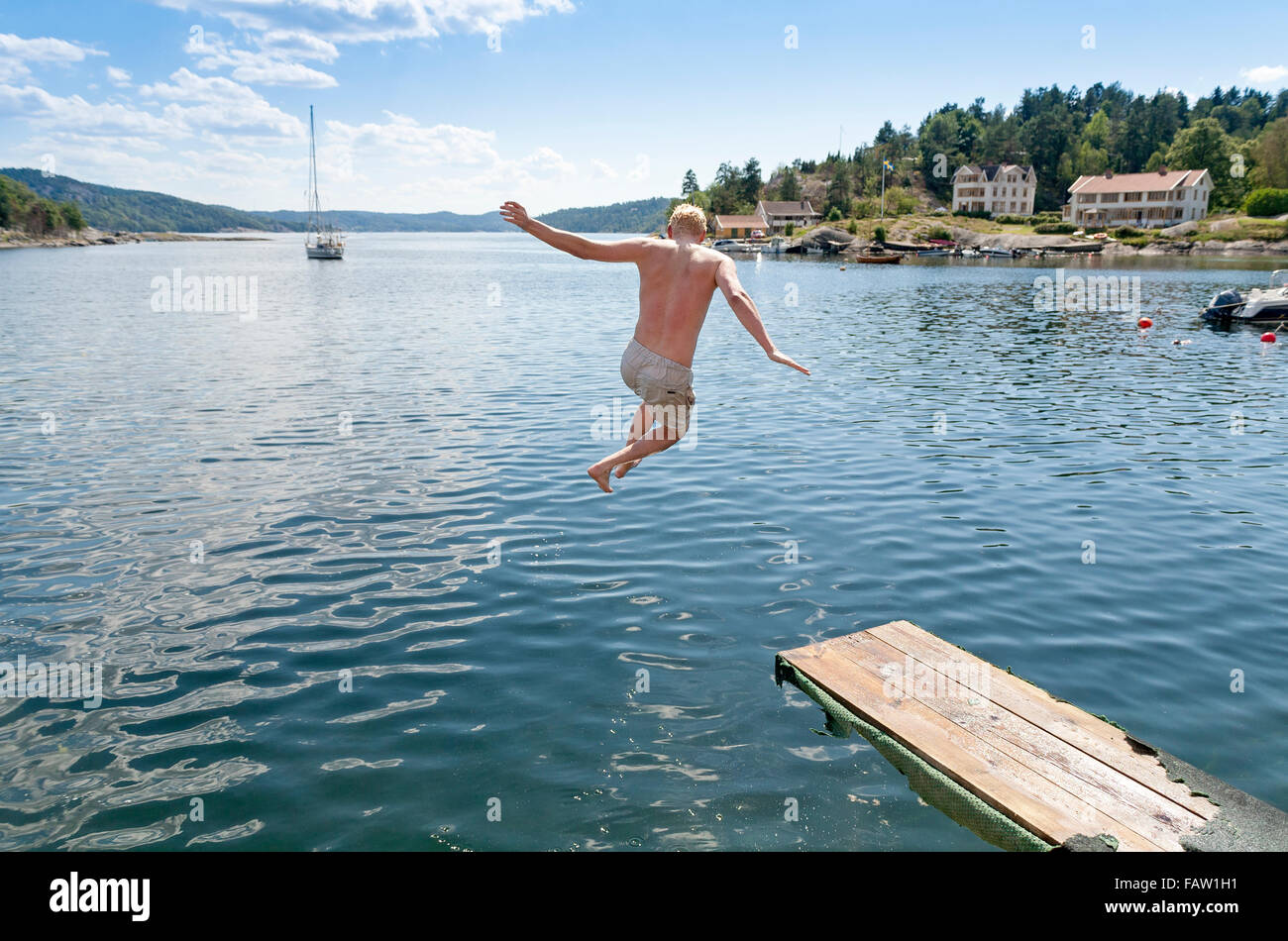 Man jumping off springboard into ocean in the summer Model Release: Yes ...