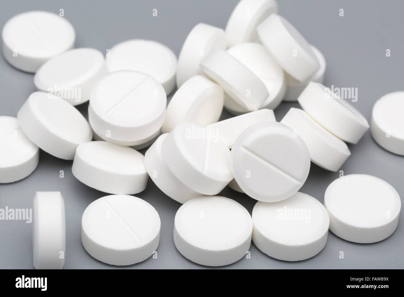 Heap of white round tablets on a gray background Stock Photo - Alamy