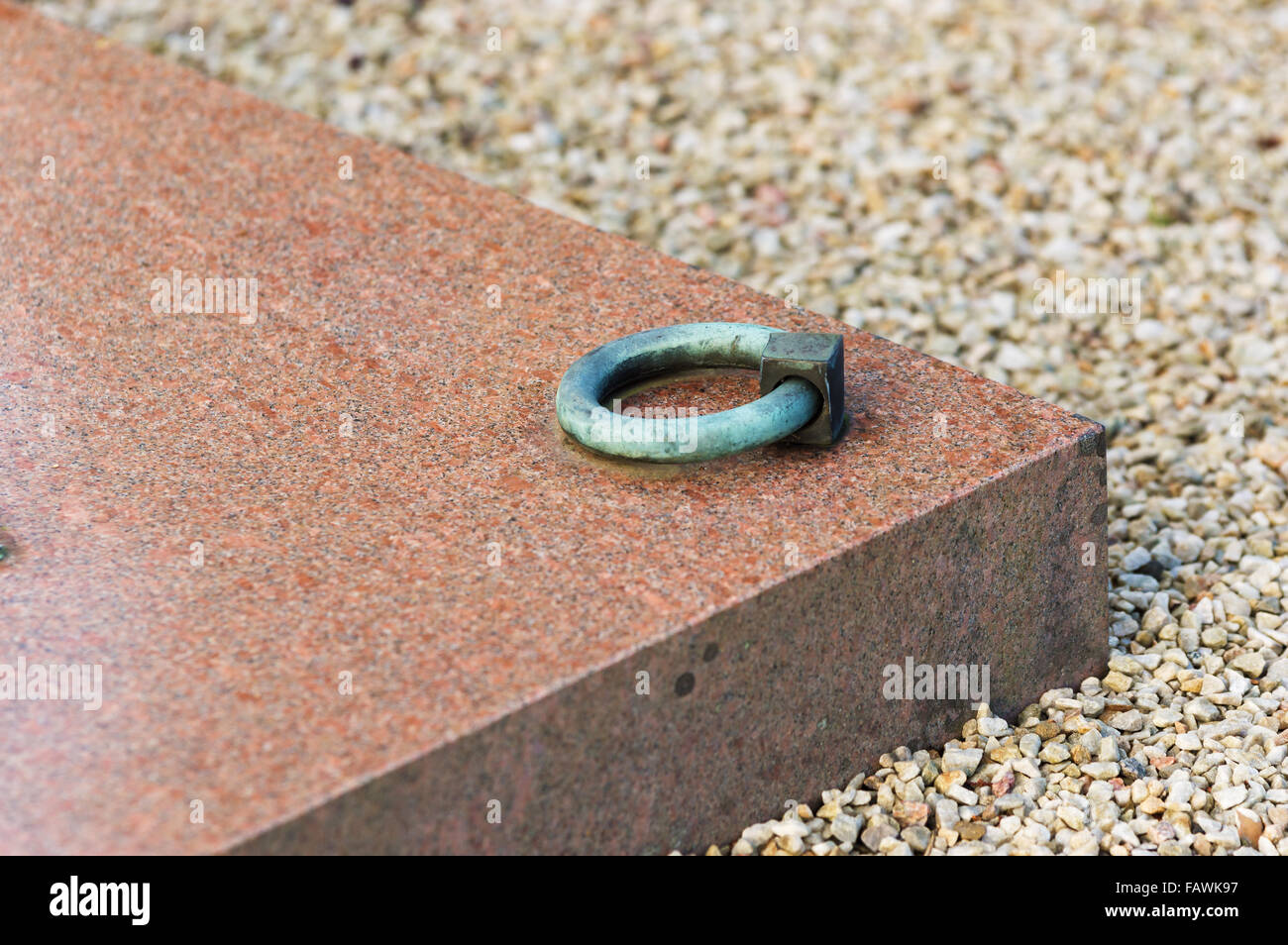 An ornamental metal ring on the corner of a polished red granite ...