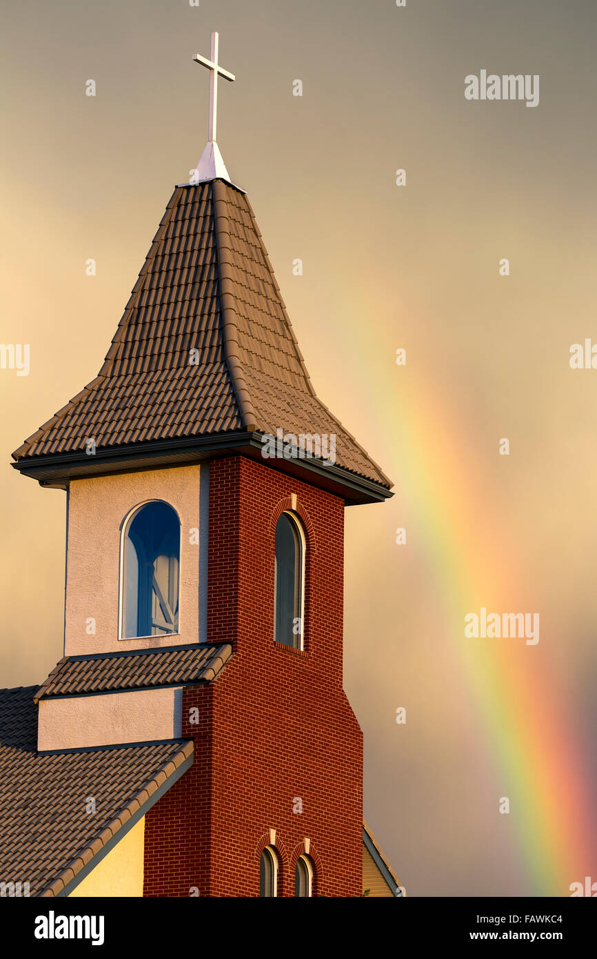 Church steeple with orange glow from the sunset and rainbow in the sky ...
