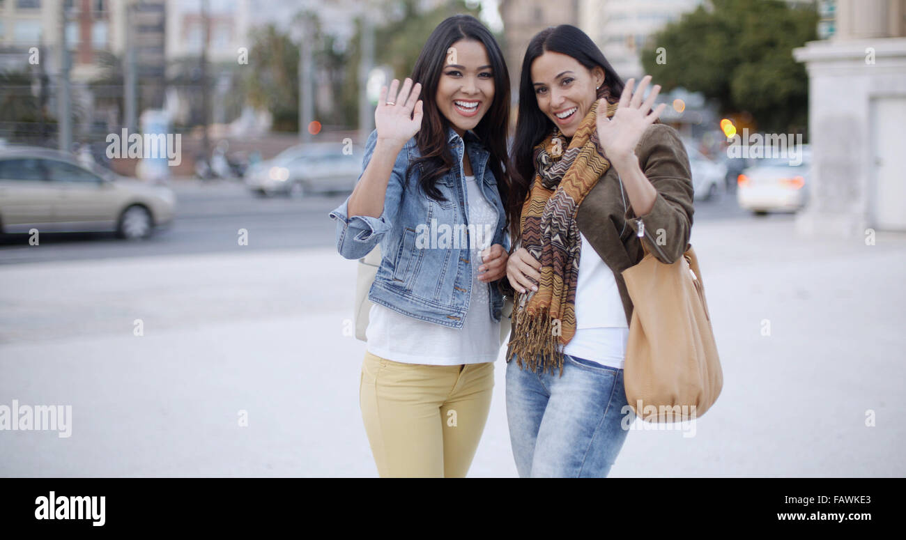 Happy young women waving at the camera Stock Photo - Alamy