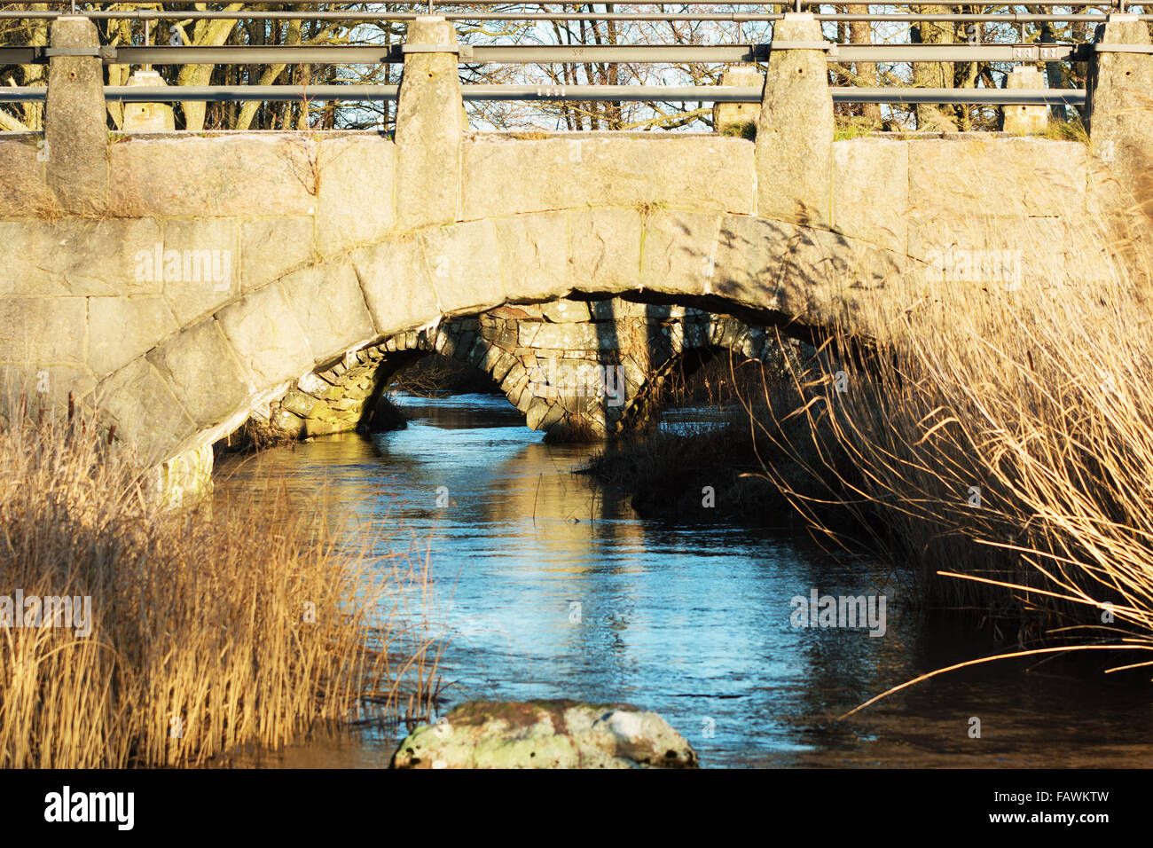 Arches under two stone bridges with a small river underneath. Reed at ...